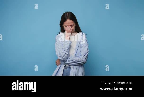 Woman expressing sadness in front of blue background during emotional ...