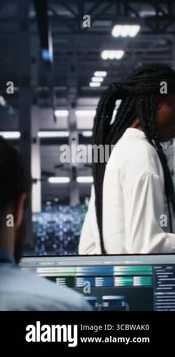 Vertical video Team of data center engineers looking over paperwork and using deep learning ...