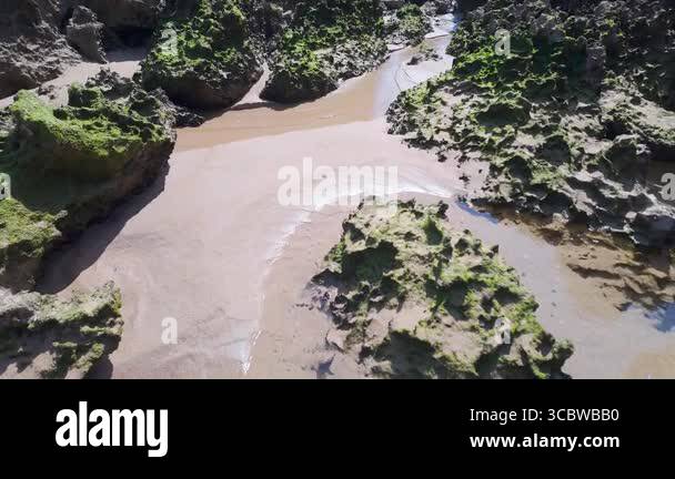 Formations of sharp rocks in the sand of the beach where small streams ...