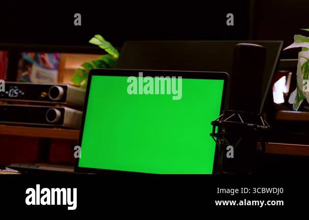 Clean desk setup in a cozy room with a laptop displaying a green screen ...