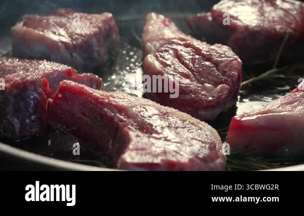 Seasoned lamb chops resting in pan with visible marbling and oil before ...