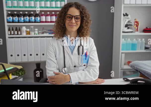 Woman doctor with curly hair smiling in a clinic office wearing a white ...
