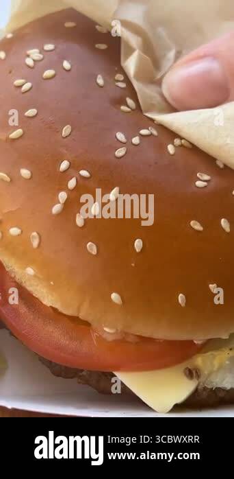 Hungry young Caucasian woman eating burger in kitchen. on the street ...