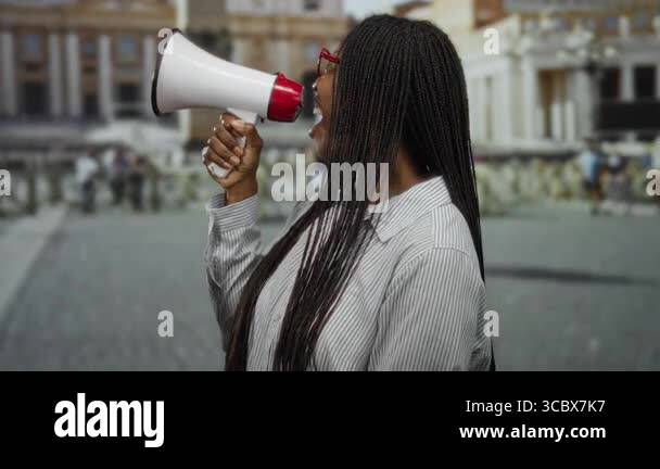 Woman shouting into megaphone with braided hair standing outdoors in ...