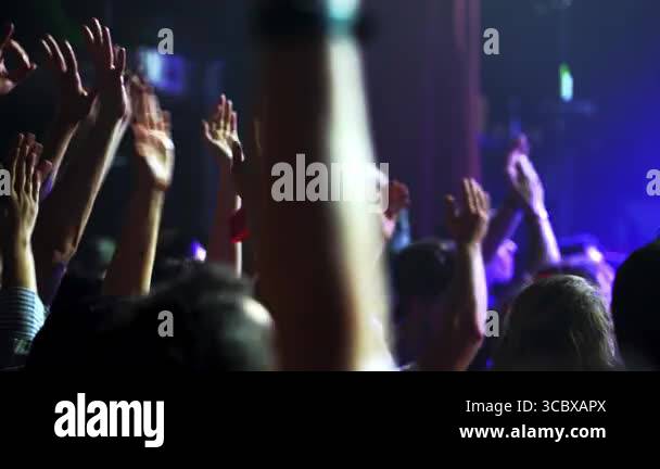 Enthusiastic fans are cheering and raising their hands, holding a red ...
