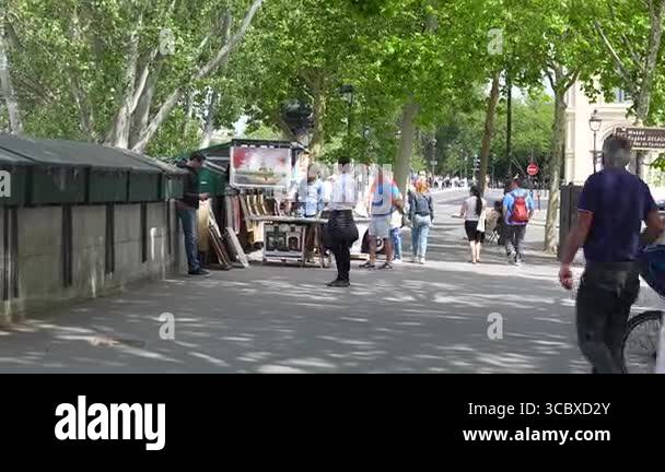 Tourists and locals stroll past open-air art stalls along the Seine ...