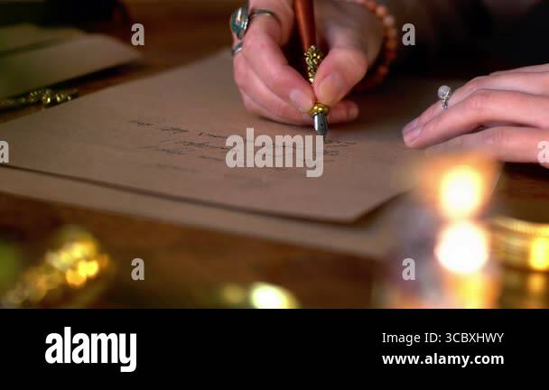 Close up of hands and handwritten letter written with antique quill pen ...
