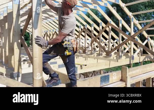 A carpenter works diligently to assemble the house roof structure of a ...