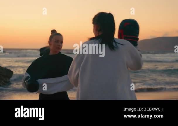 Determined female fighter practicing defensive boxing on the beach ...