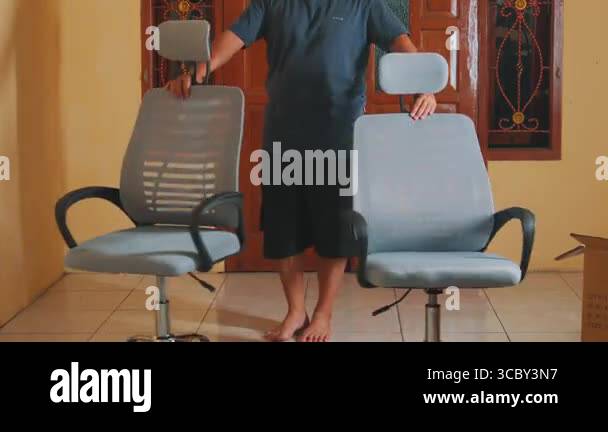 A person assembling two ergonomic office chairs in a room with beige ...