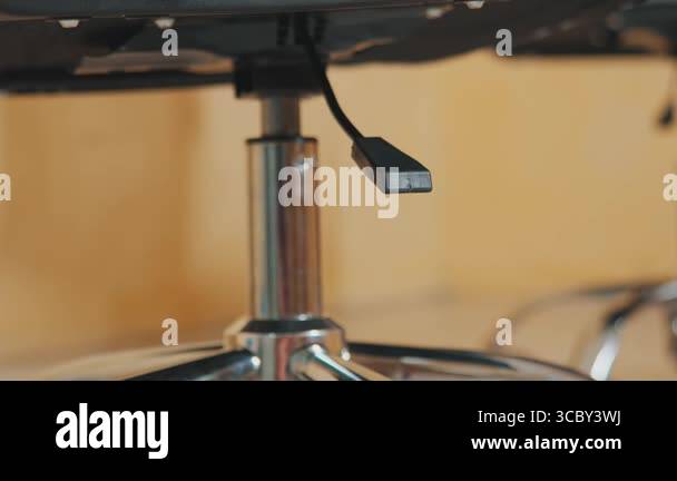 Close-up of an office chair's height adjustment lever, showcasing the ...