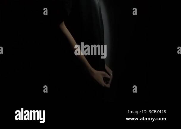 A person standing in a dark environment, illuminated by a small light ...