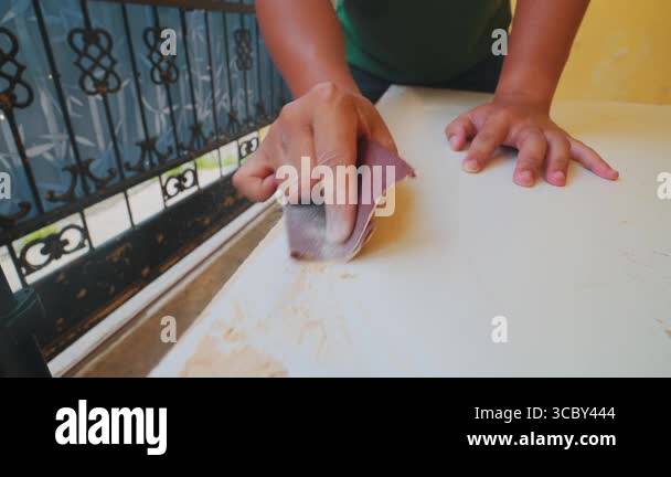 A person sanding a wooden surface, focusing on a smooth finish. The ...