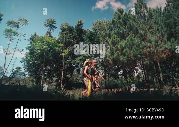 A low-angle wide shot of a traditional Javanese couple walking hand-in-hand in a beautiful ...