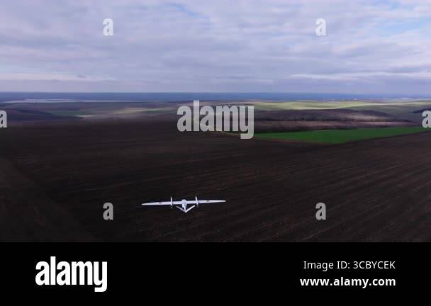 Small aircraft is soaring above vast farmland, with dark soil and green ...