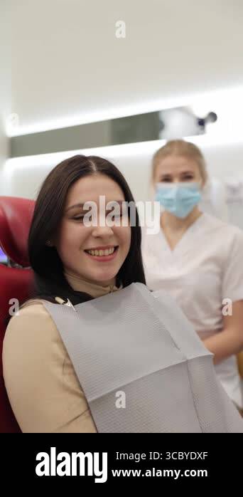 A cheerful and happy patient smiles brightly during a routine dental ...