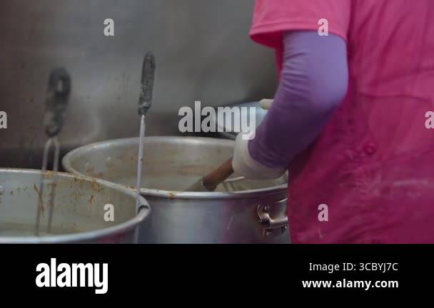Slow motion close-up of Korean street vendor straining boiled noodles ...