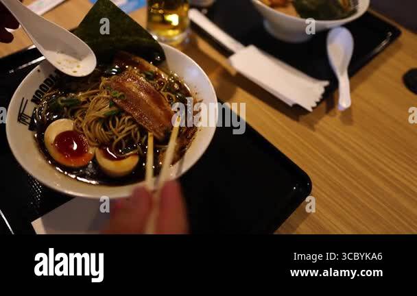 Person eating ramen with chopsticks at a table Stock Video Footage - Alamy