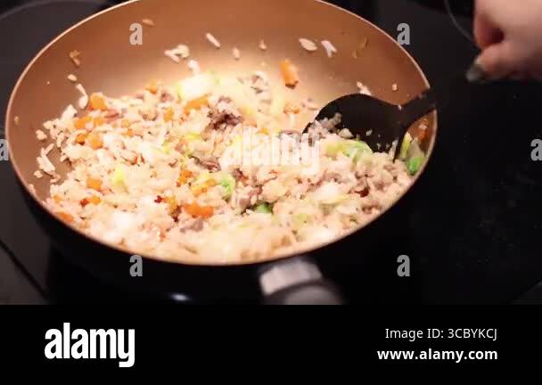 Stirring and cooking fried rice on a stovetop Stock Video Footage - Alamy