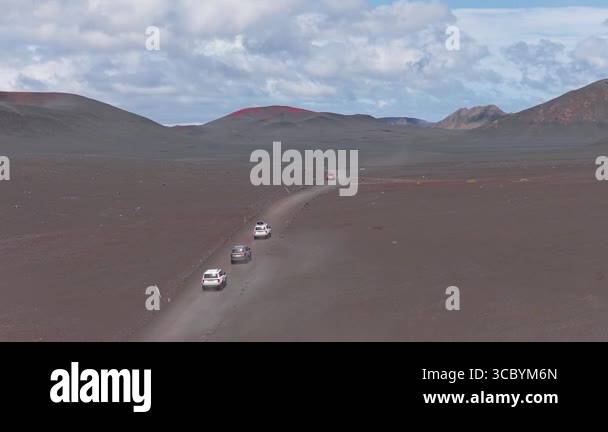 Four vehicles traverse a barren volcanic landscape in Iceland, with ...