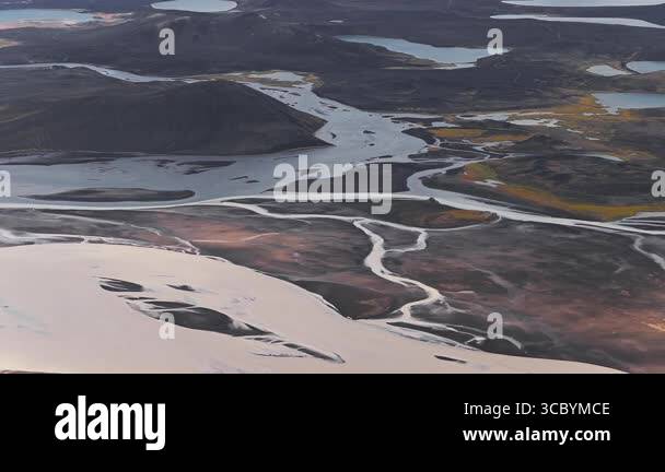 Aerial sweep over braided rivers on a dark volcanic plain in Iceland ...
