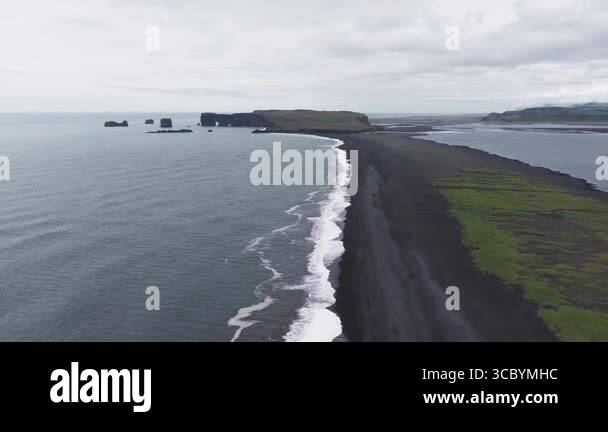 Aerial view of Iceland's black sand beach, featuring sea stacks, gentle ...