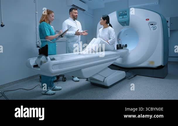 Doctor in white gown talking to patient after MRI. Patient lying at MRI ...