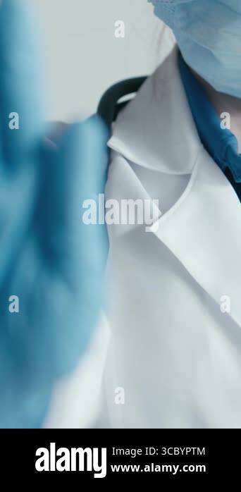 A healthcare worker in a white coat and gloves demonstrates caution ...