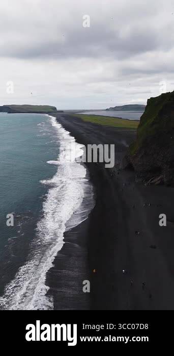 Aerial view of Reynisfjara's black sand beach in Iceland. Waves crash ...