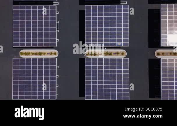 Symmetrical top-down drone view of large solar panel structures covering a modern parking lot in ...