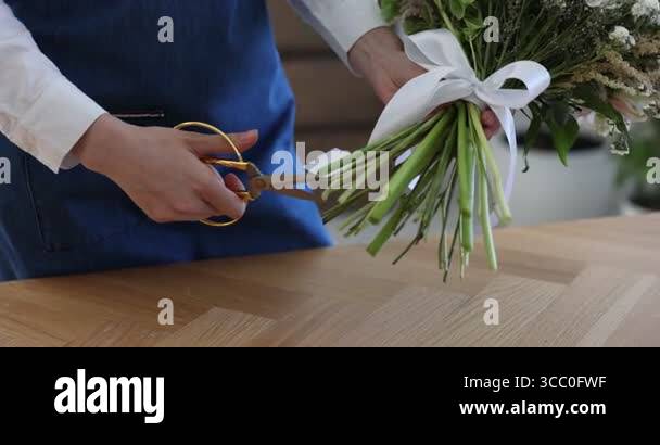 Woman pruning stems of flowers at wooden table indoors, closeup Stock ...