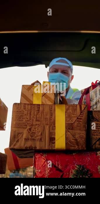 Delivery service. deliveryman in protective mask. courier unloads boxes ...