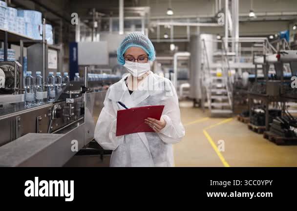 Female quality control inspector wearing protective clothing and mask ...