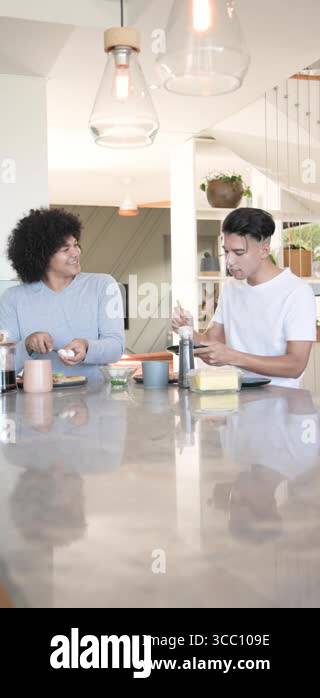 Vertical video: Hunger driving male friends to counter, slicing eggs, brewing coffee for ...