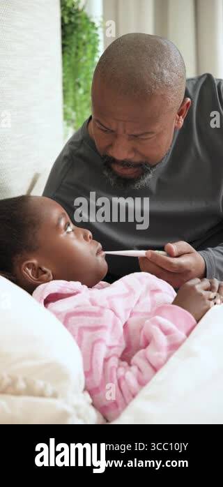 Vertical video: African American father checking daughter temperature ...