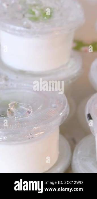 Asian dessert with coconut milk, pandan jelly in plastic cup. A cute ...