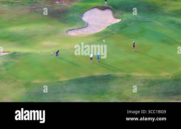 Golfers putt on a lush green under warm sunset lighting at Royal Pines ...