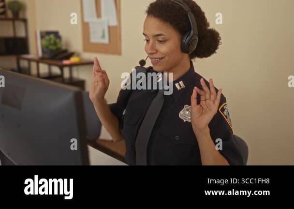 Woman police officer wearing headset working at computer in station ...
