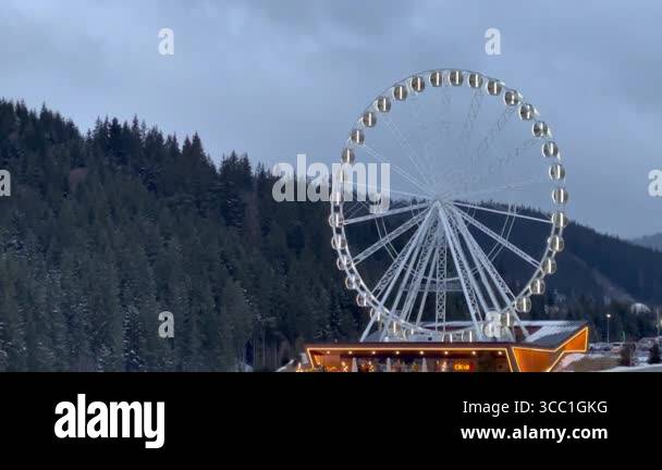 Large ferris wheel rotating slowly against a backdrop of a mountain ...
