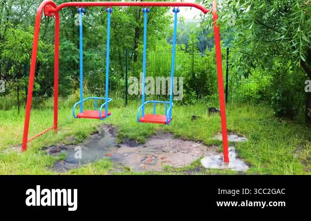 Children's metal swing during rain. Circles on the water from falling ...