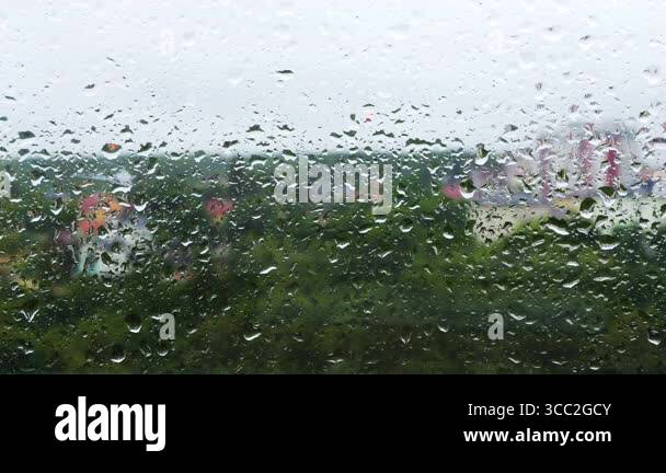 Water drops roll down the window glass during rain against the ...