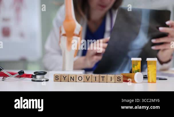 Female professional examines X-ray near Synovitis on cubes and model of ...