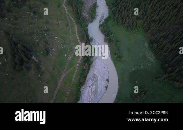 Dawn breaks over a tranquil mountain valley as a river meanders through ...