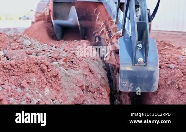Heavy trenching machinery digs into dry ground, creating trench in ...