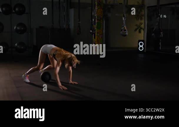 A woman with a beautiful sculpted body is doing warm-up and stretching ...