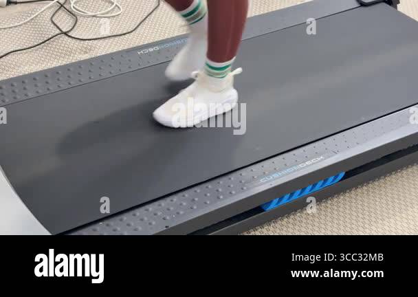 Close-up of feet walking on a treadmill in a home gym, captured in slow ...