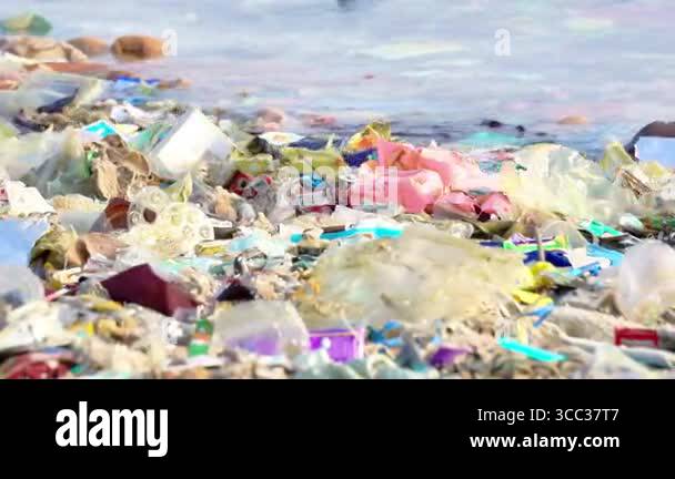 Various plastic waste scattered on the beach. Garbage pollutes and ...