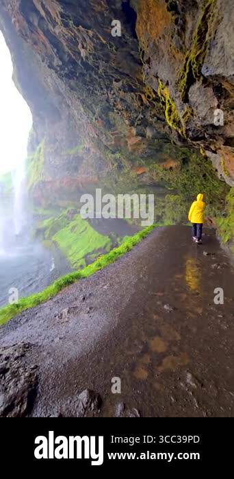A traveler dressed in a bright yellow coat walks along a muddy path ...