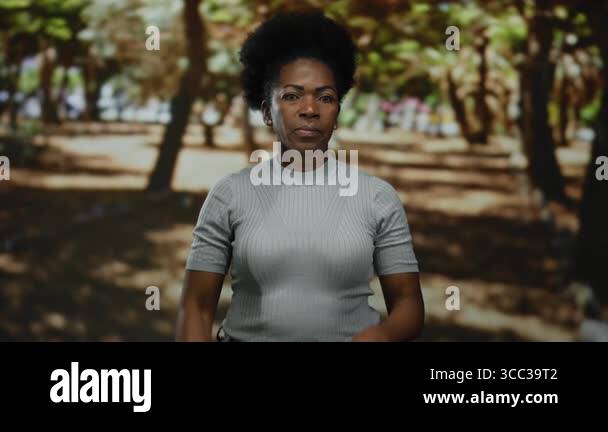 Woman gesturing oath in park with trees, demonstrating a serious ...
