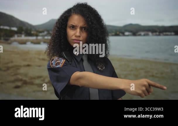 Woman police officer furrows brow and points finger on street by ...